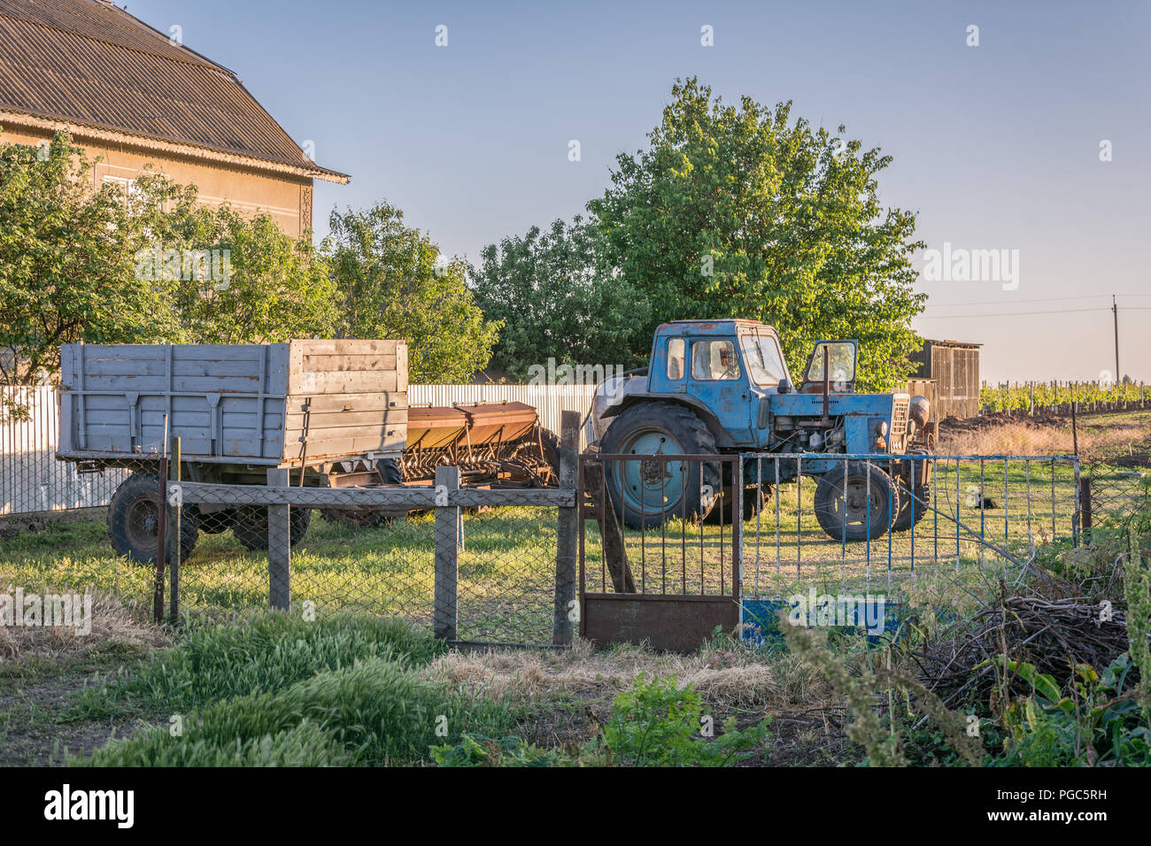 Old blue tractor, trailer and plow at sunset Stock Photo - Alamy