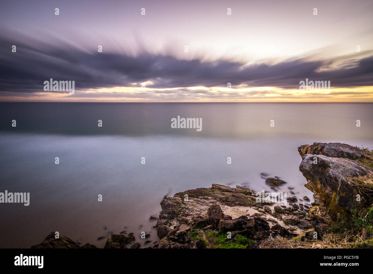 Long exposure of cloudy sky over ocean and beach Stock Photo - Alamy