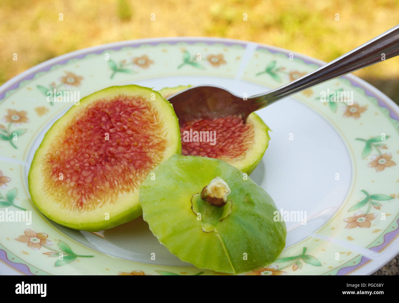 Fresh, juicy sliced green fig with spoon on it on the saucer Stock ...