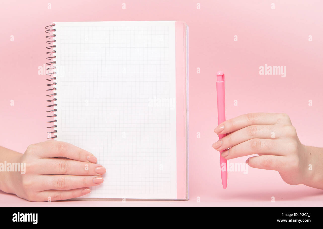 Notebook and pen in hand on pink background with copy space.Business ...