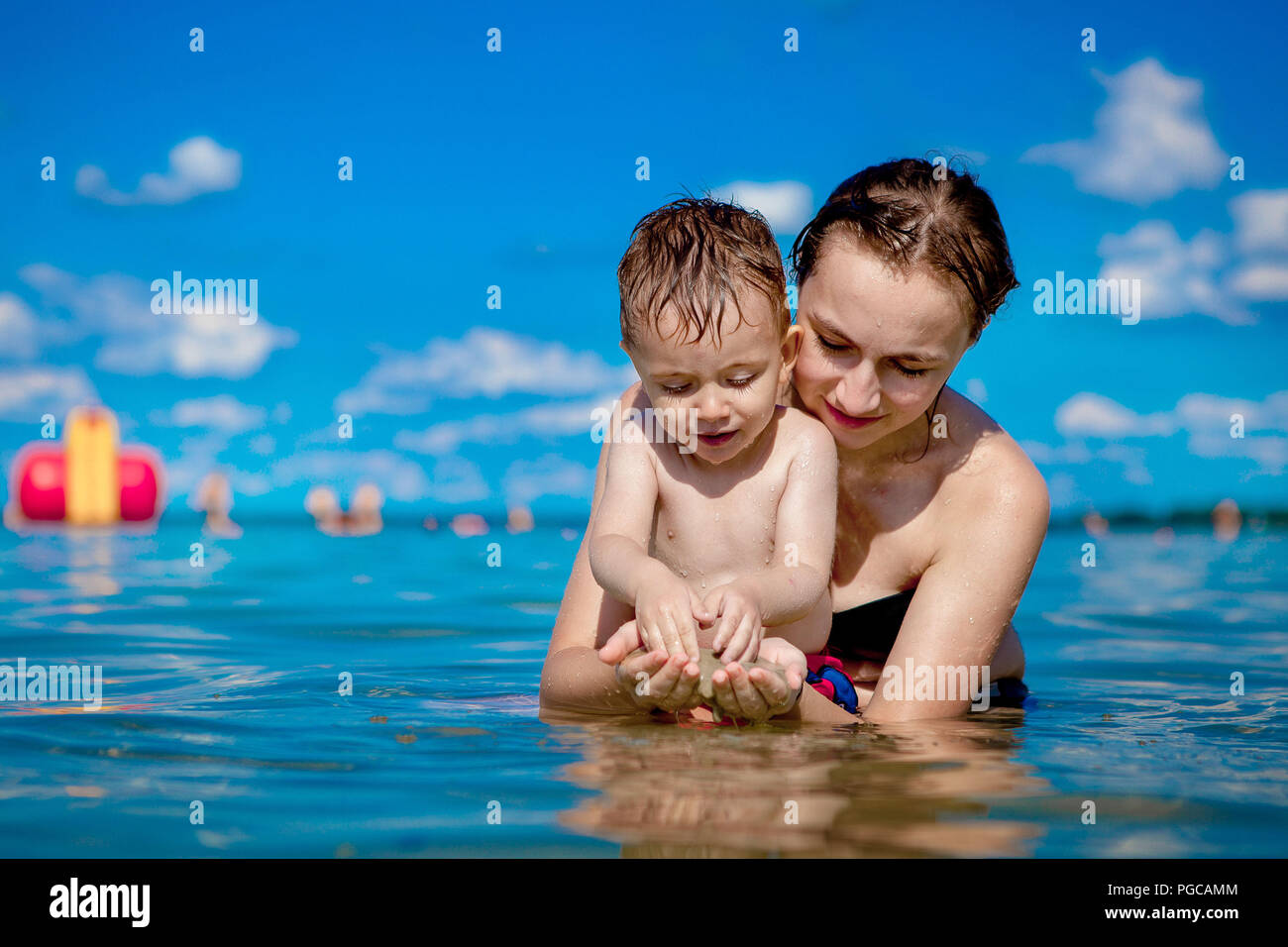 young mother with a little boy playing with water on the lake in the ...
