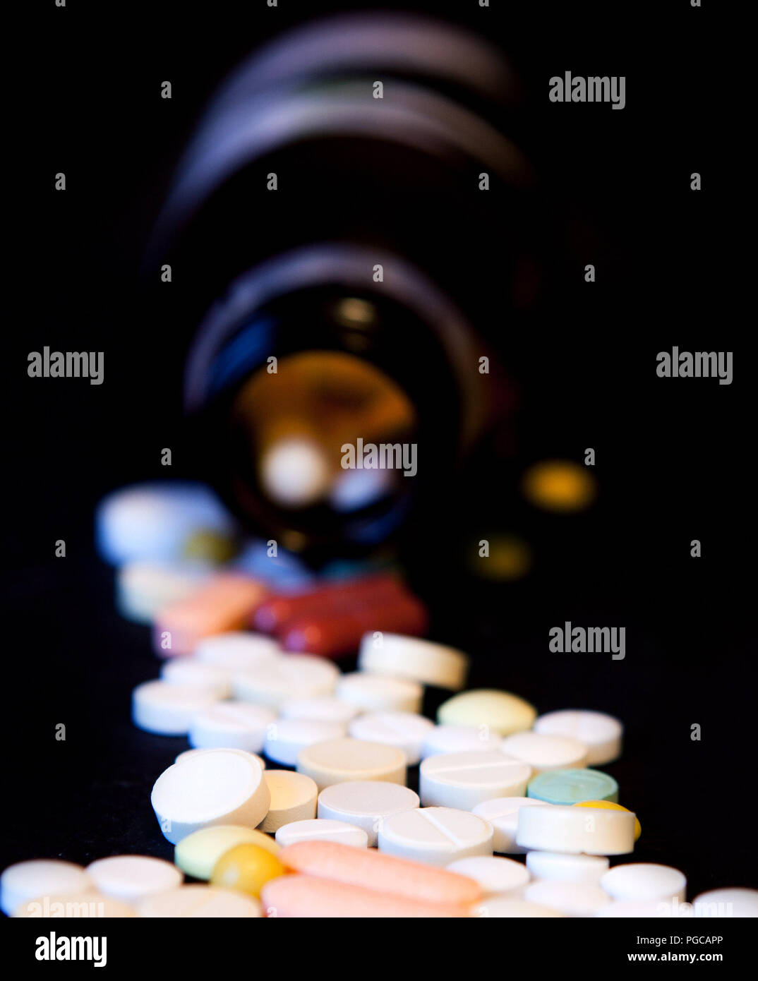 A bottle of spilled pills on black background. Levitating tablets ...