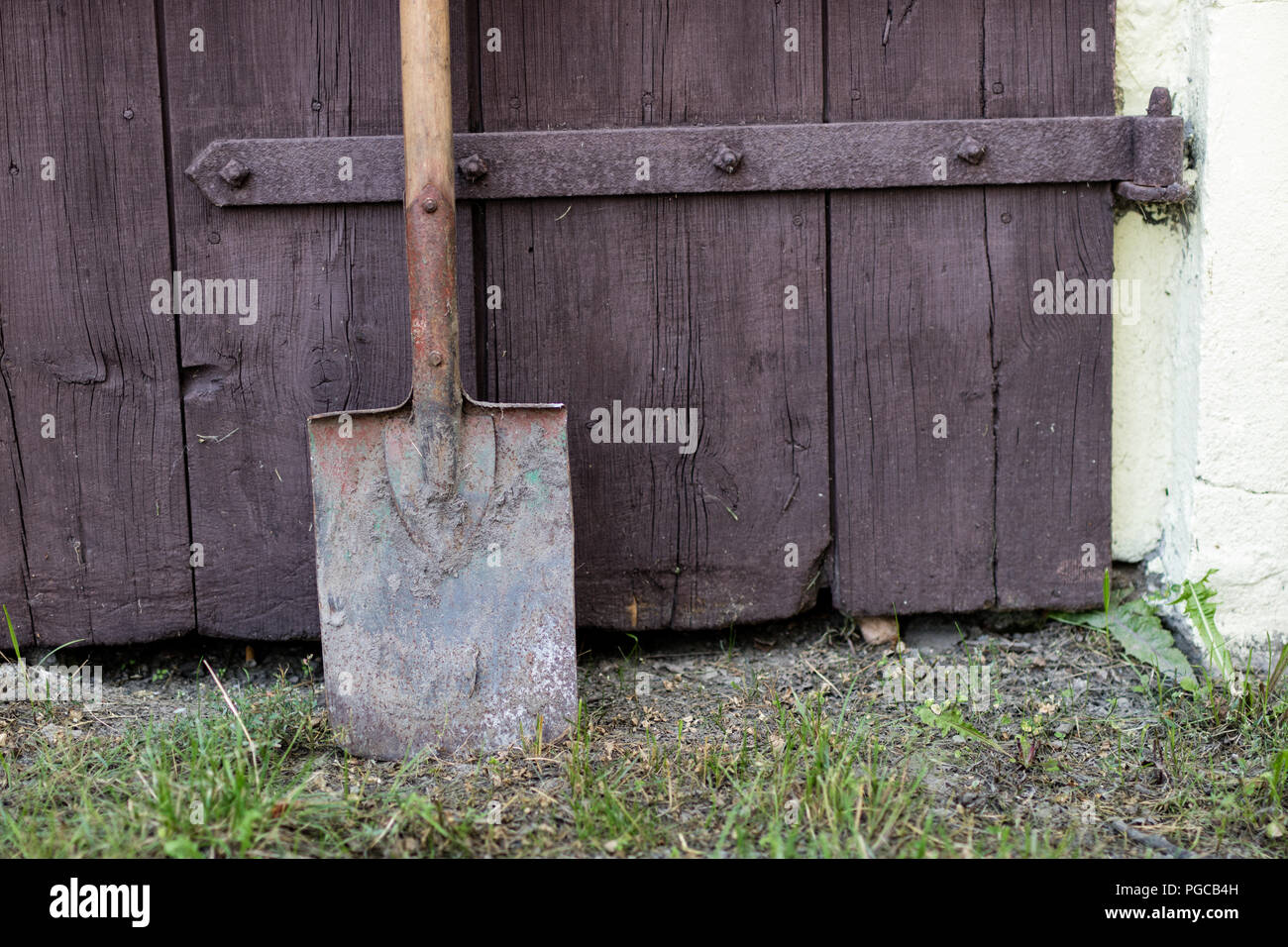 An old garden spade leaning against a wooden door. Tools for working in ...