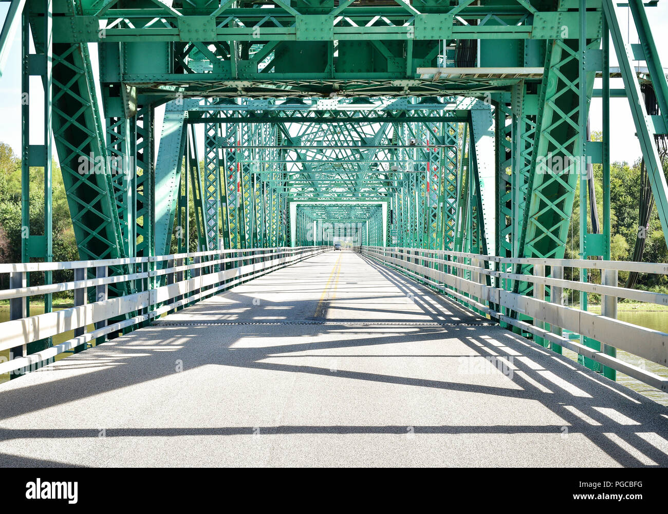 The perspective of a steel bridge crossing a river Stock Photo - Alamy