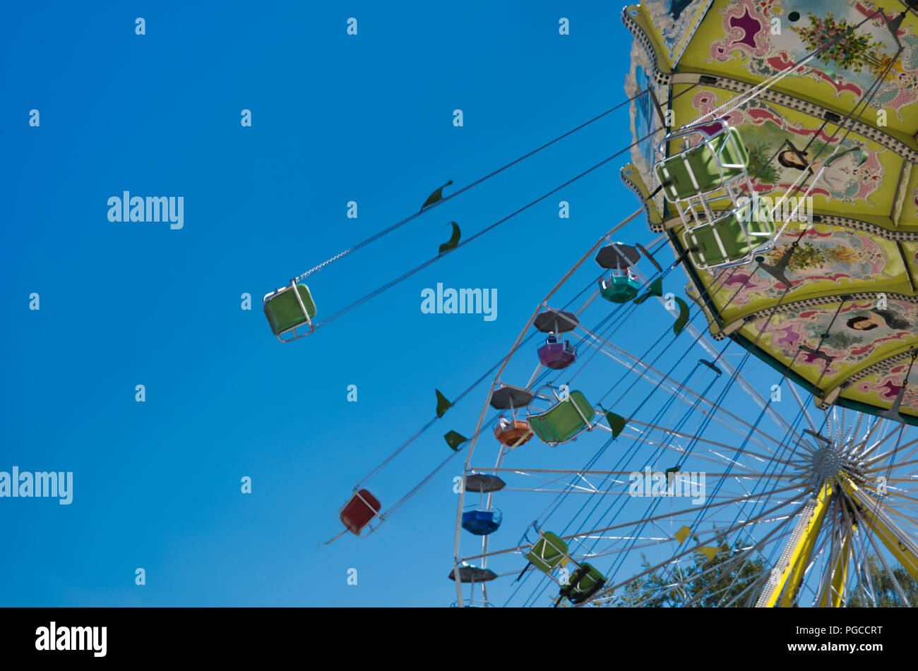 Colorful chain carousel in ride with ferris wheel and blue light cloudy ...