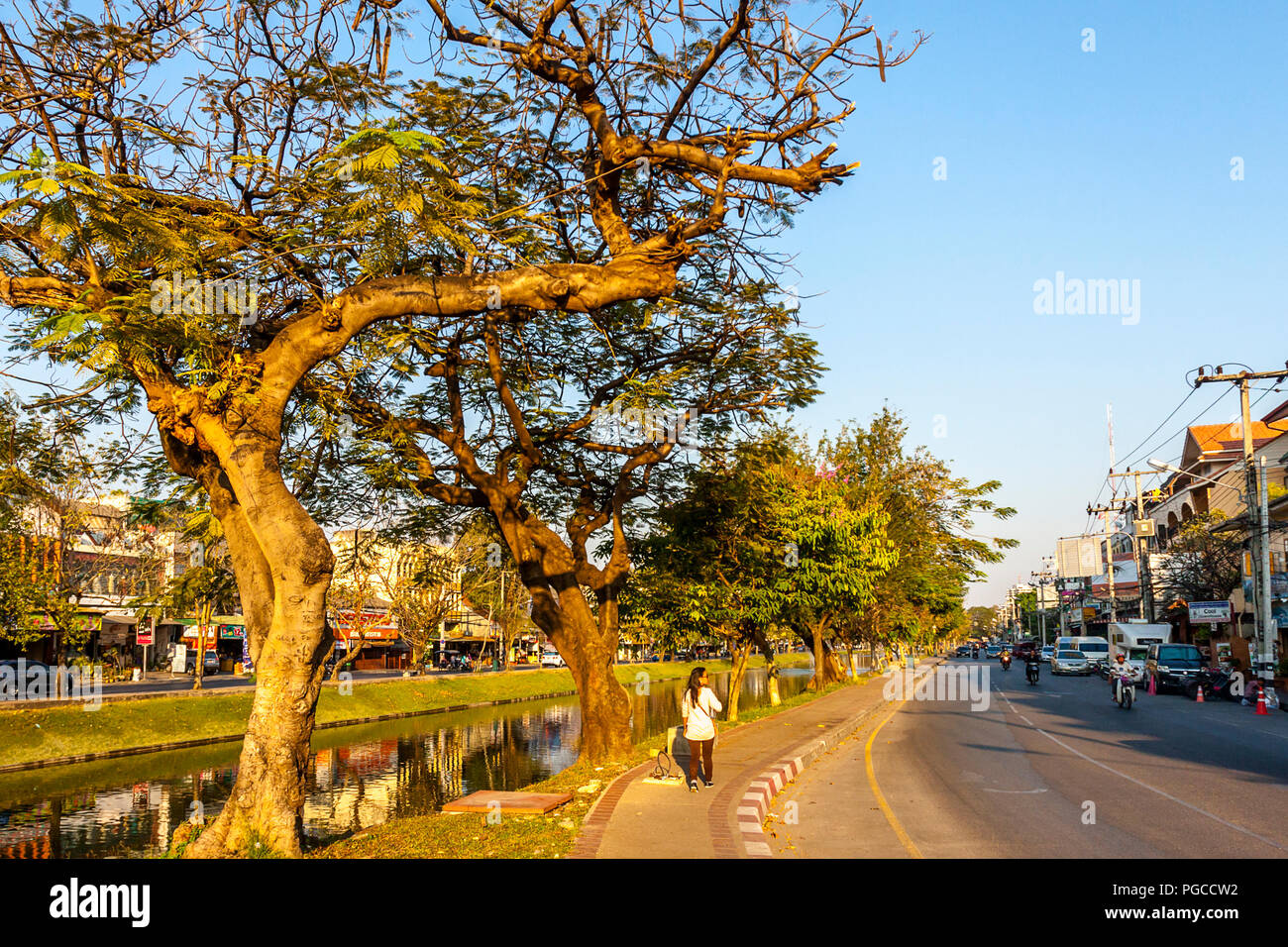 View of an Asian girl walking on the sidewalk between the moat and ...