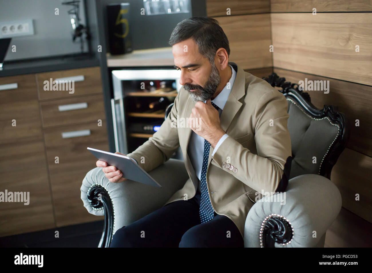 Senior businessman with digital tablet sitting on armchair Stock Photo ...