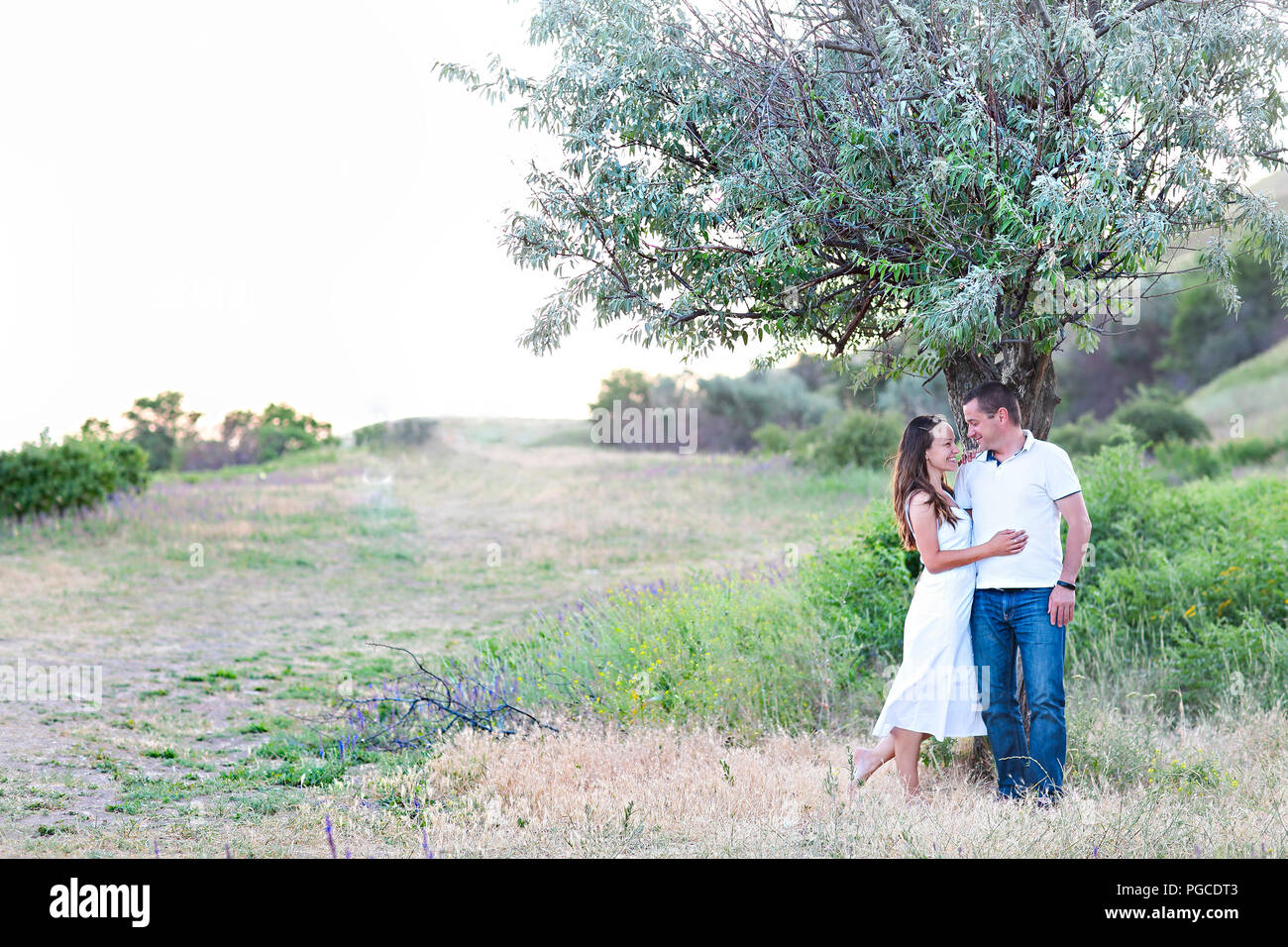 Happy couple posing on a summer day under a tree Stock Photo - Alamy