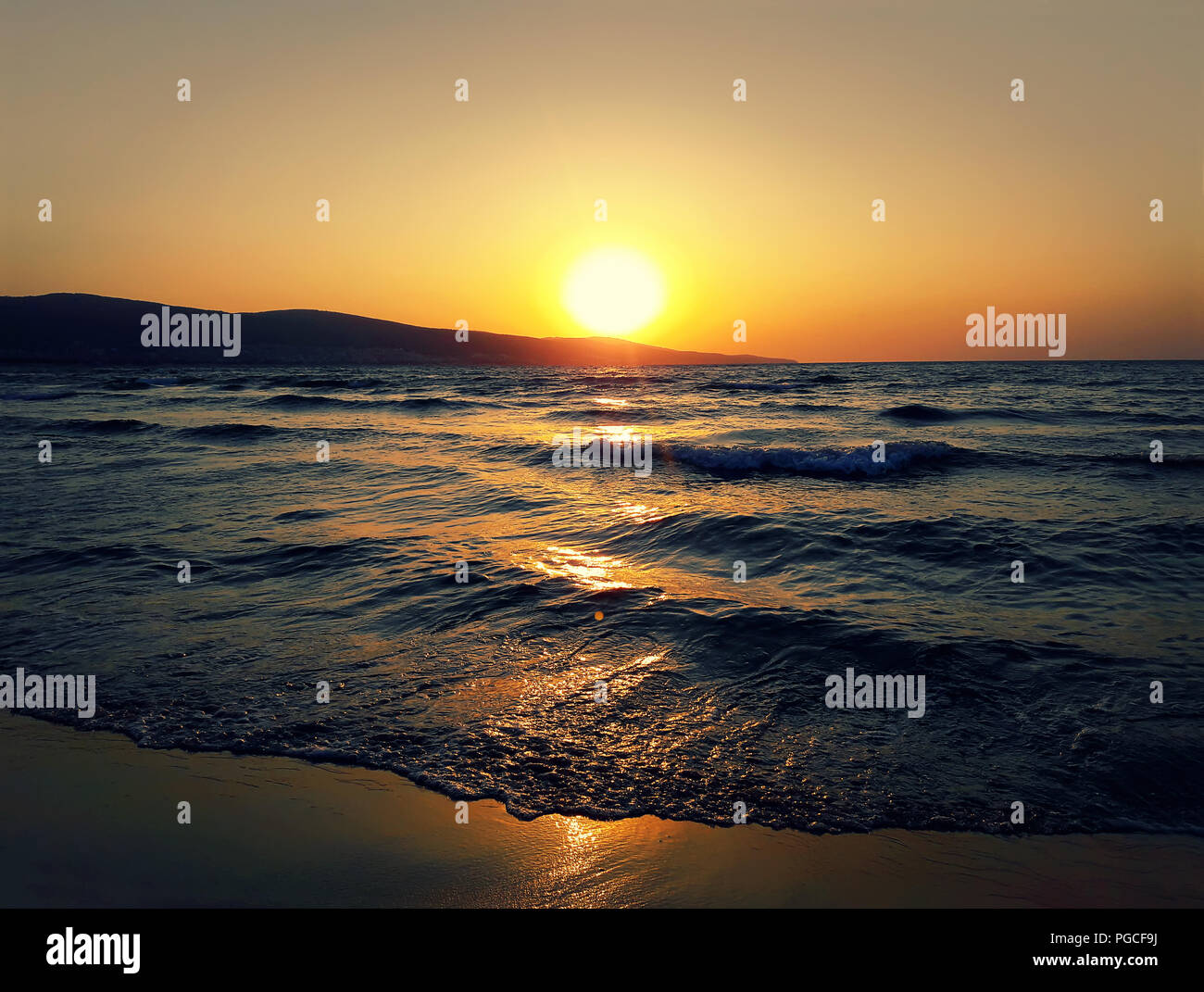 Beautiful sunset by the sea. Small waves and clear sky Stock Photo - Alamy