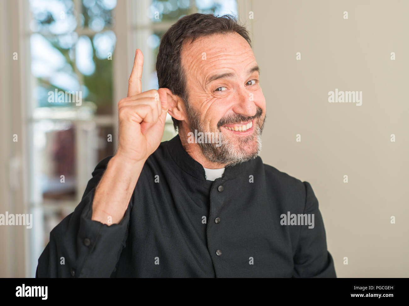 Christian priest man surprised with an idea or question pointing finger ...