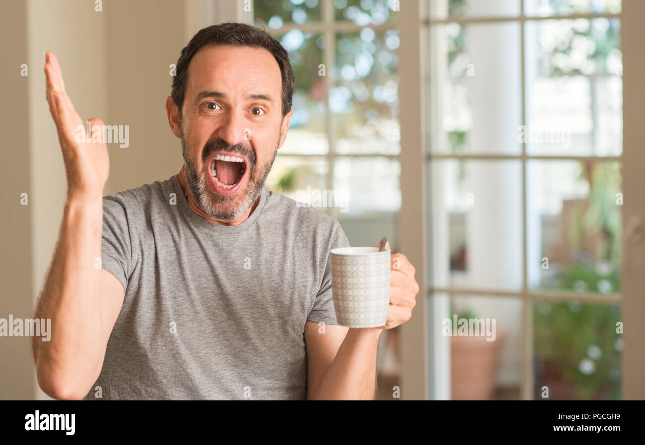 Middle age man drinking coffee in a cup very happy and excited, winner ...