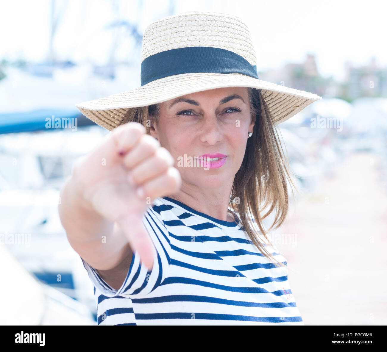 Beautiful middle age woman standing in marina with angry face, negative ...