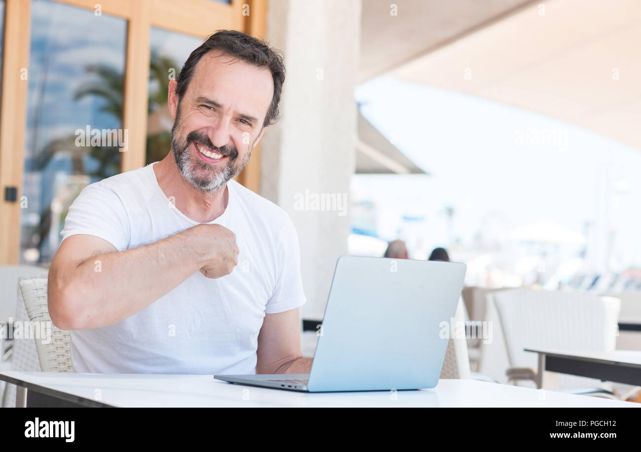 Handsome senior man using laptop at restaurant with surprise face ...