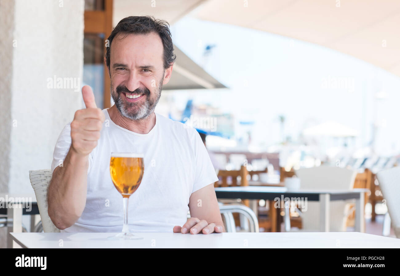Handsome senior man drinking beer at restaurant happy with big smile ...