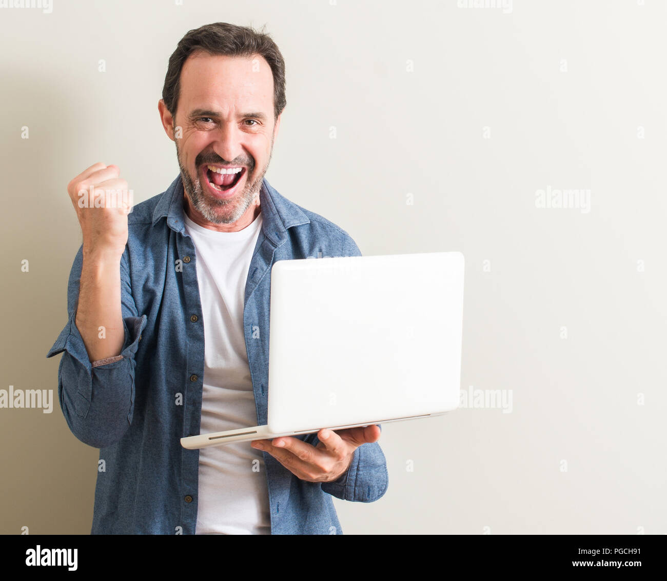 Senior man using laptop computer screaming proud and celebrating ...