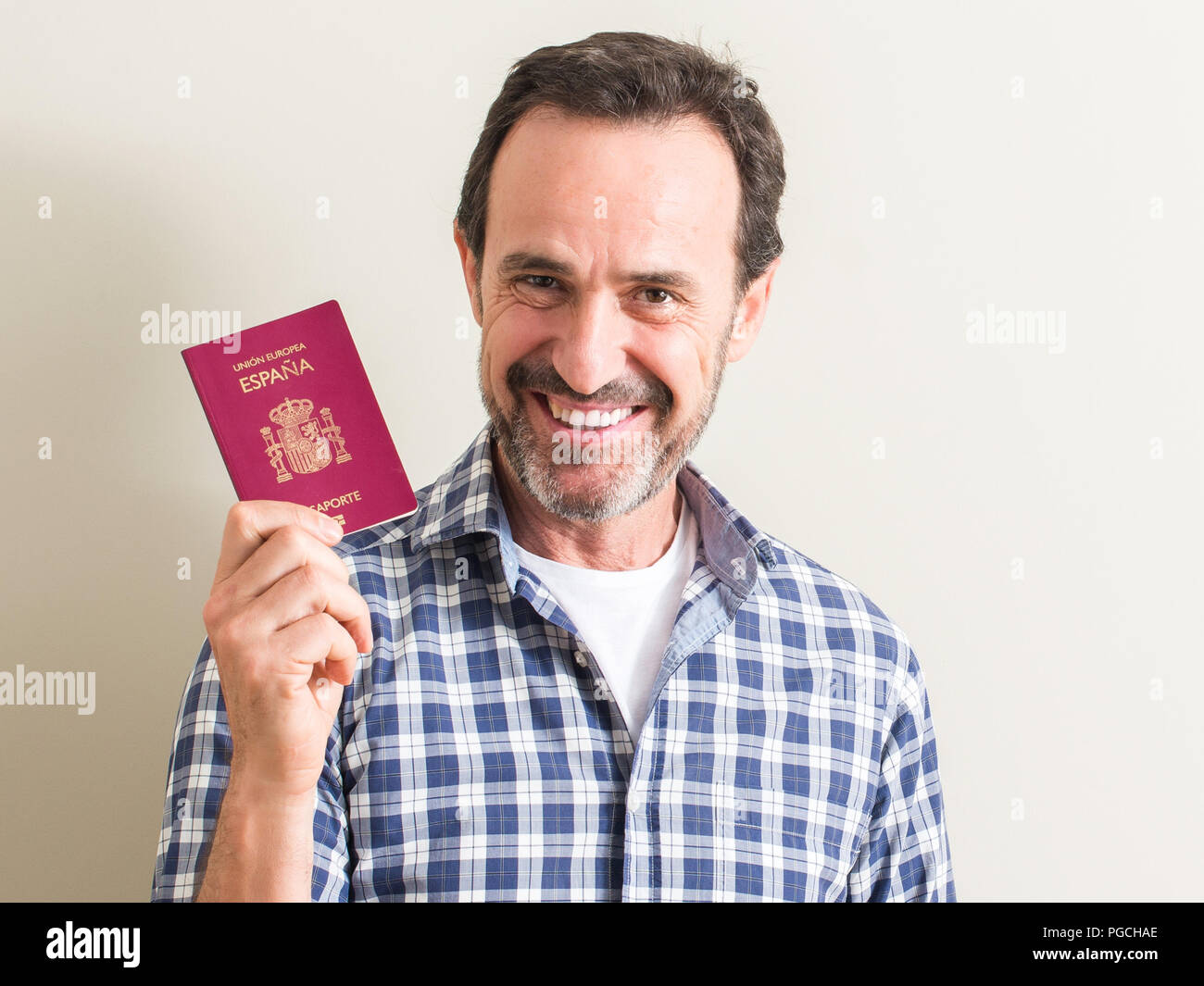 Senior man holding spanish passport with a happy face standing and ...