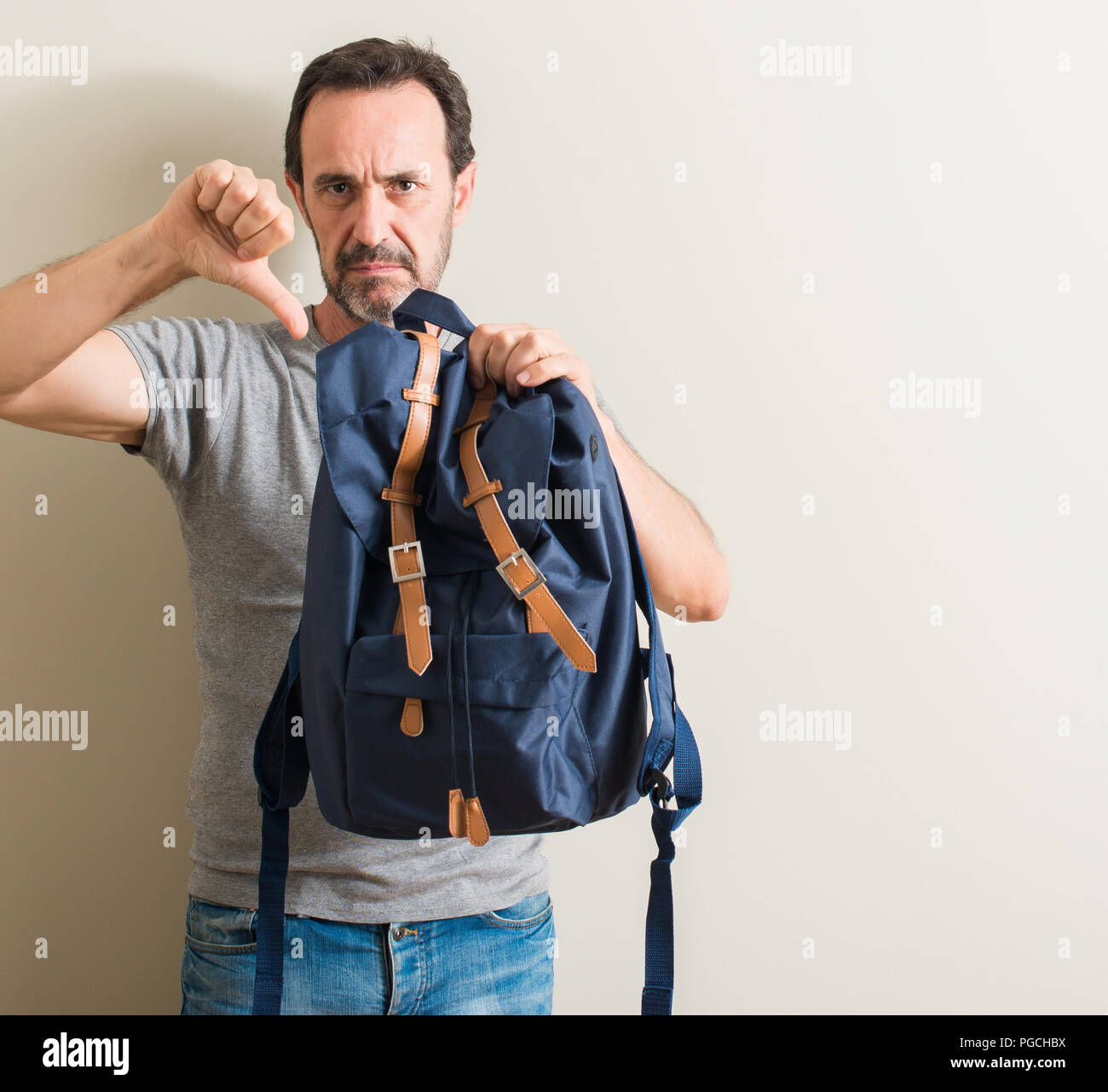 Senior man using backpack with angry face, negative sign showing ...