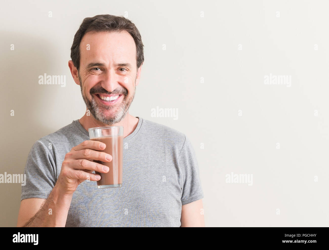 Senior man drinking chocolate milk shake with a happy face standing and ...