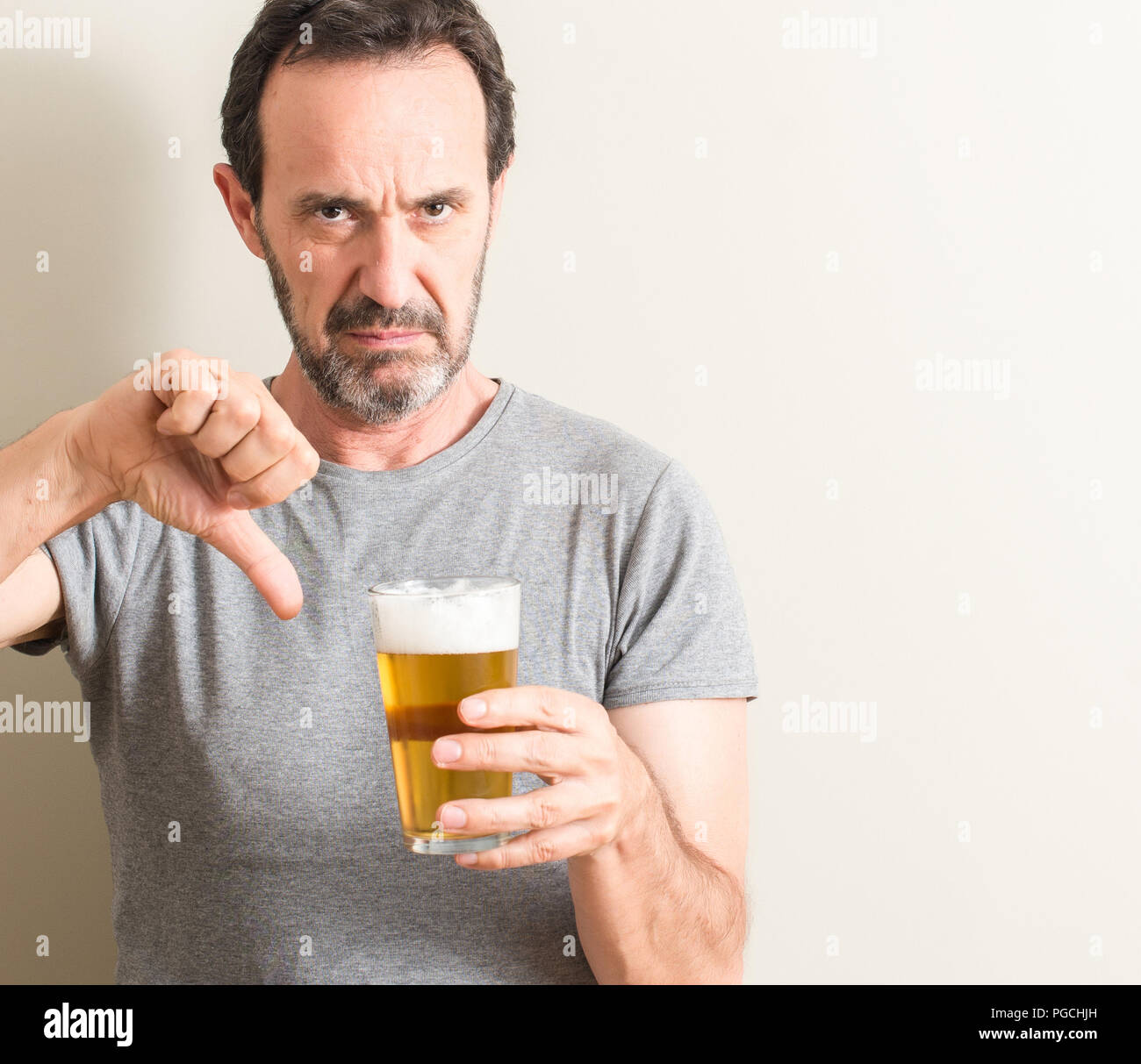 Senior man drinking beer with angry face, negative sign showing dislike ...