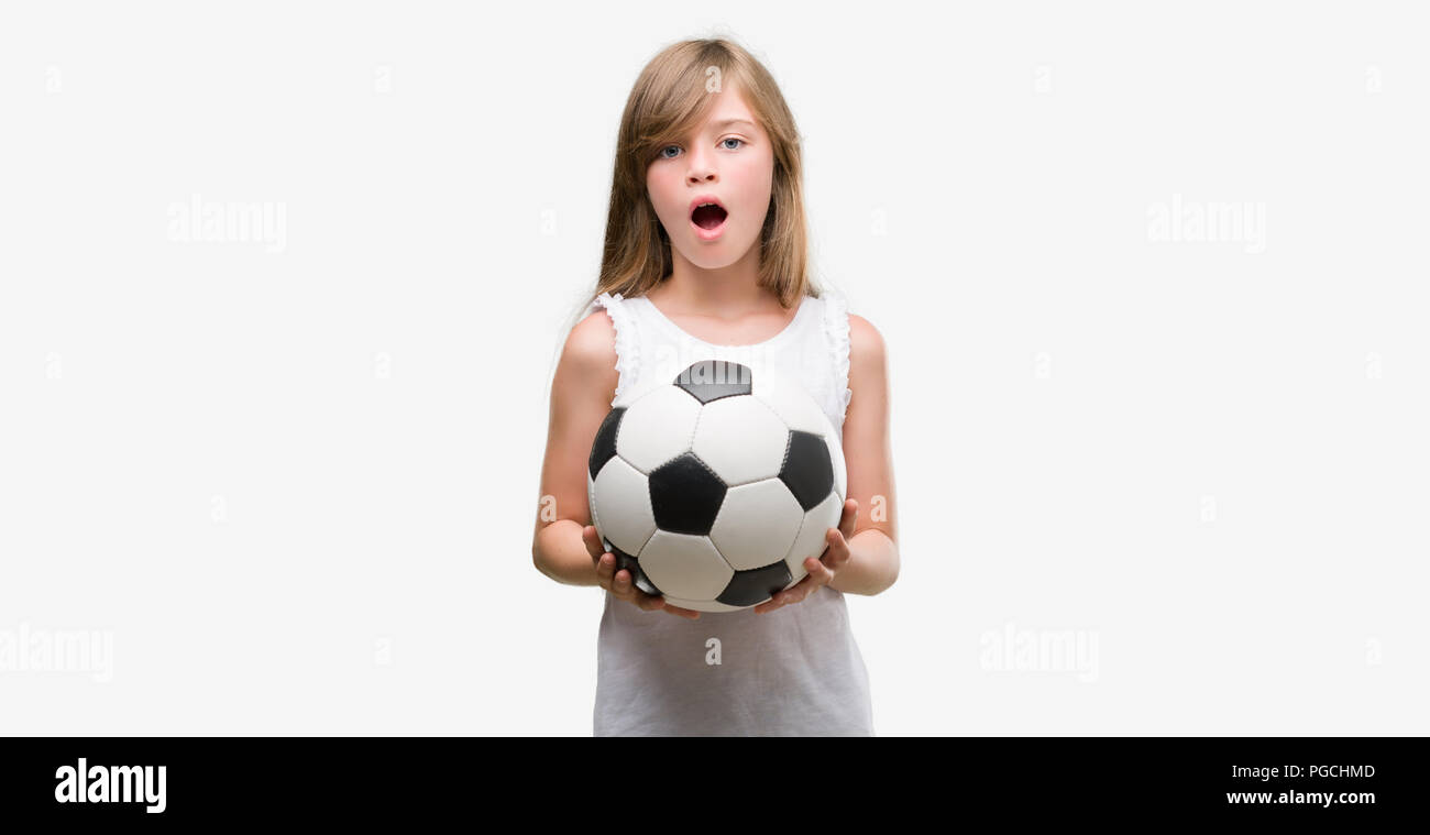 Young blonde toddler holding football ball scared in shock with a ...