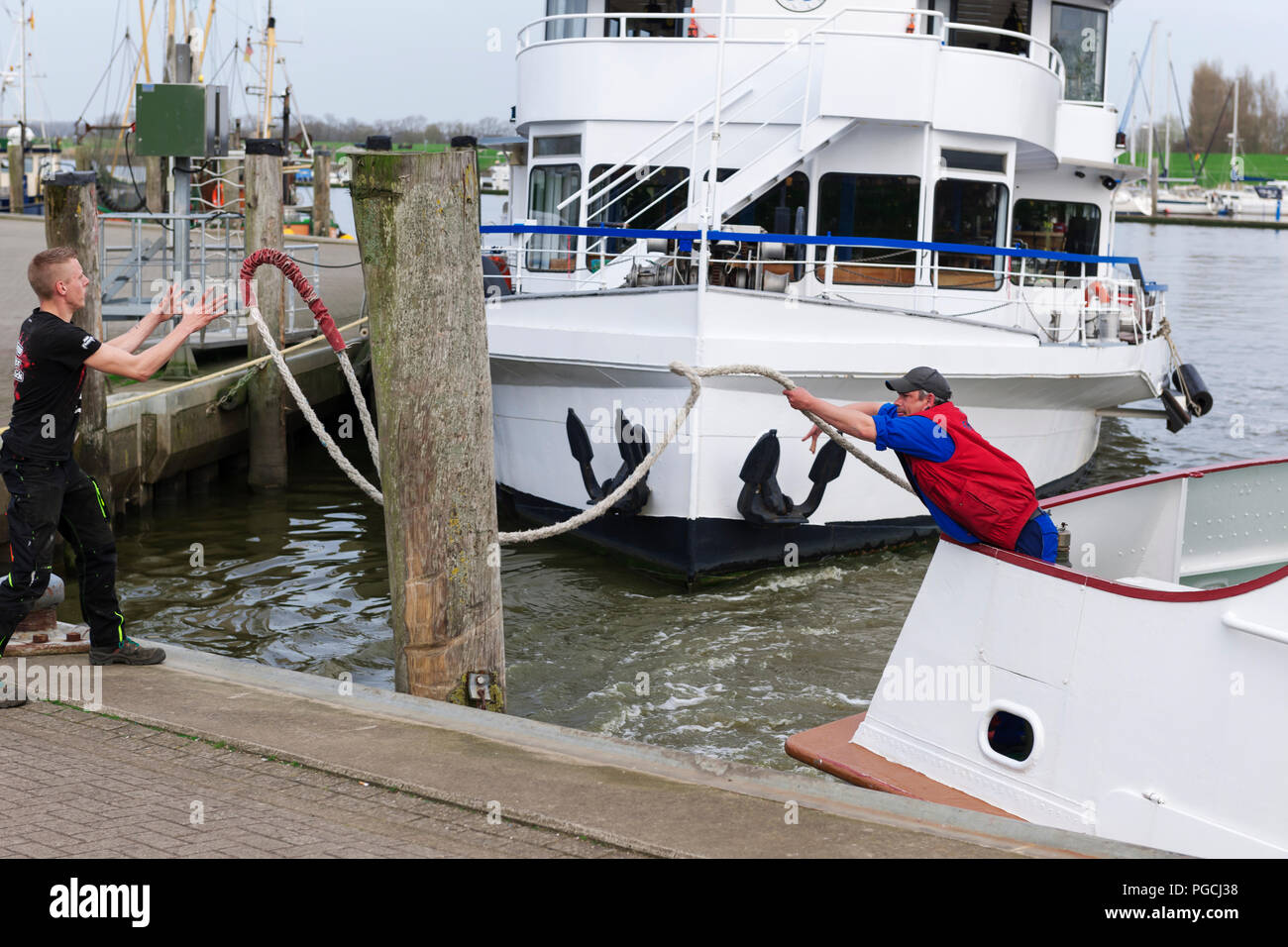 Two boatmen throw a rope at the docking maneuver of an incoming ...