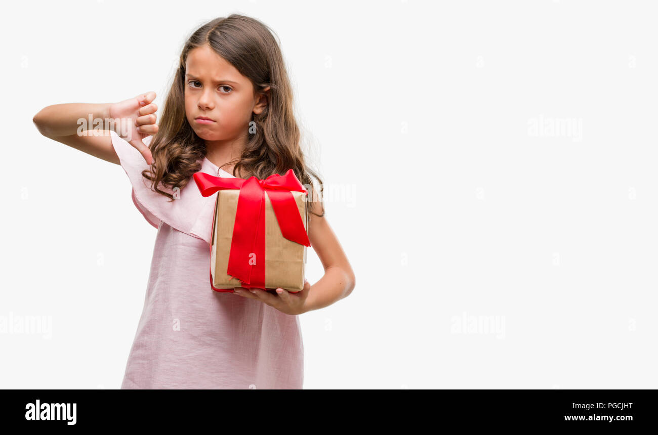 Brunette hispanic girl holding a gift with angry face, negative sign ...