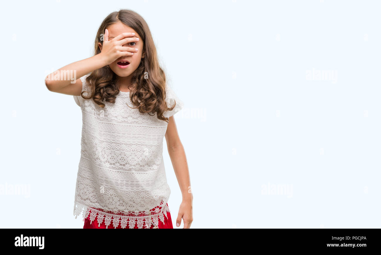 Brunette hispanic girl peeking in shock covering face and eyes with ...