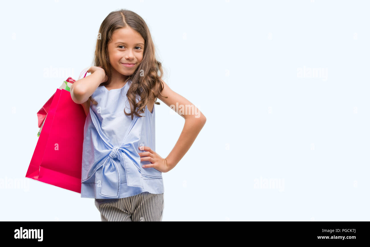 Brunette hispanic girl holding shopping bags with a happy face standing ...