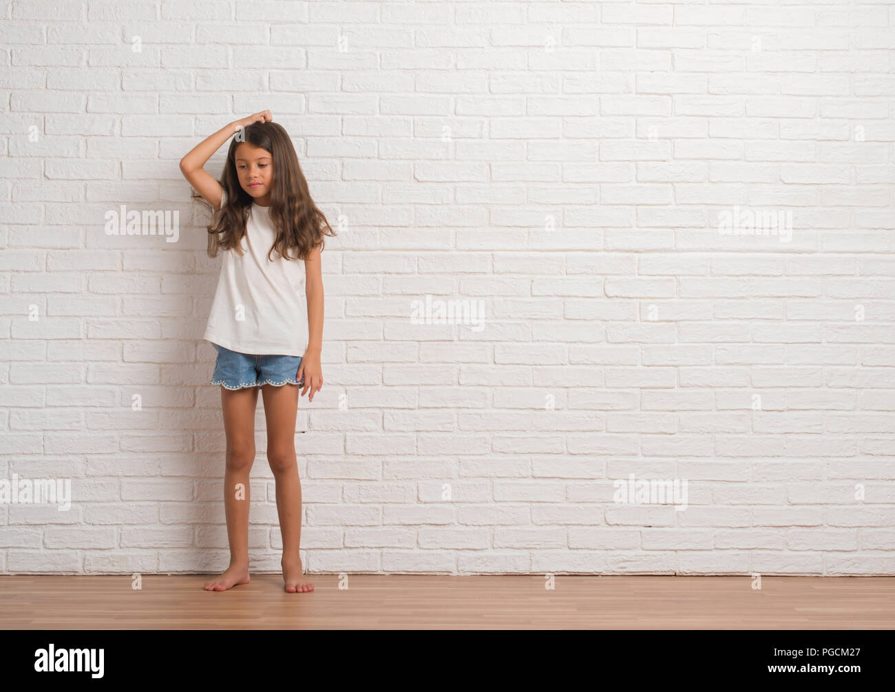 Young hispanic kid stading over white brick wall confuse and wonder ...