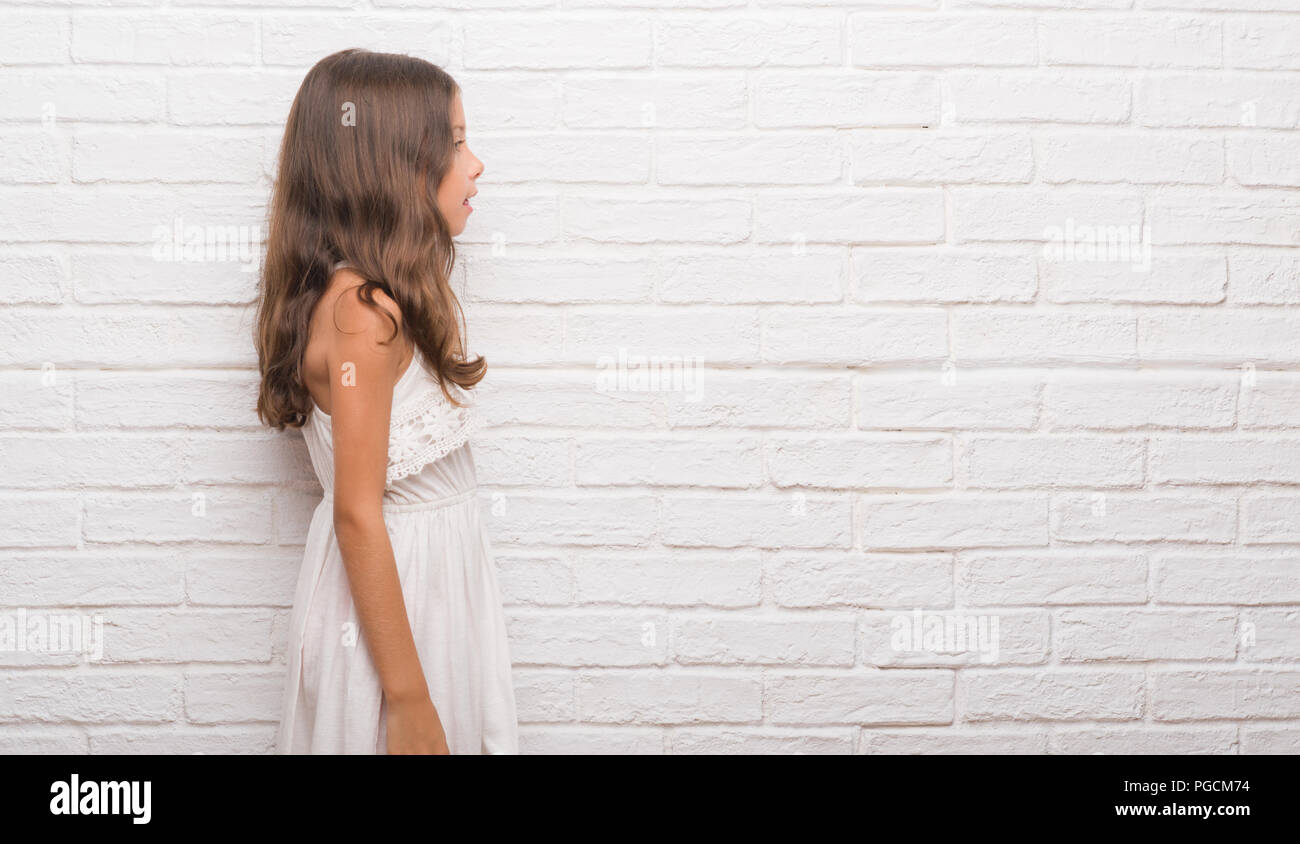 Young hispanic kid over white brick wall looking to side, relax profile ...