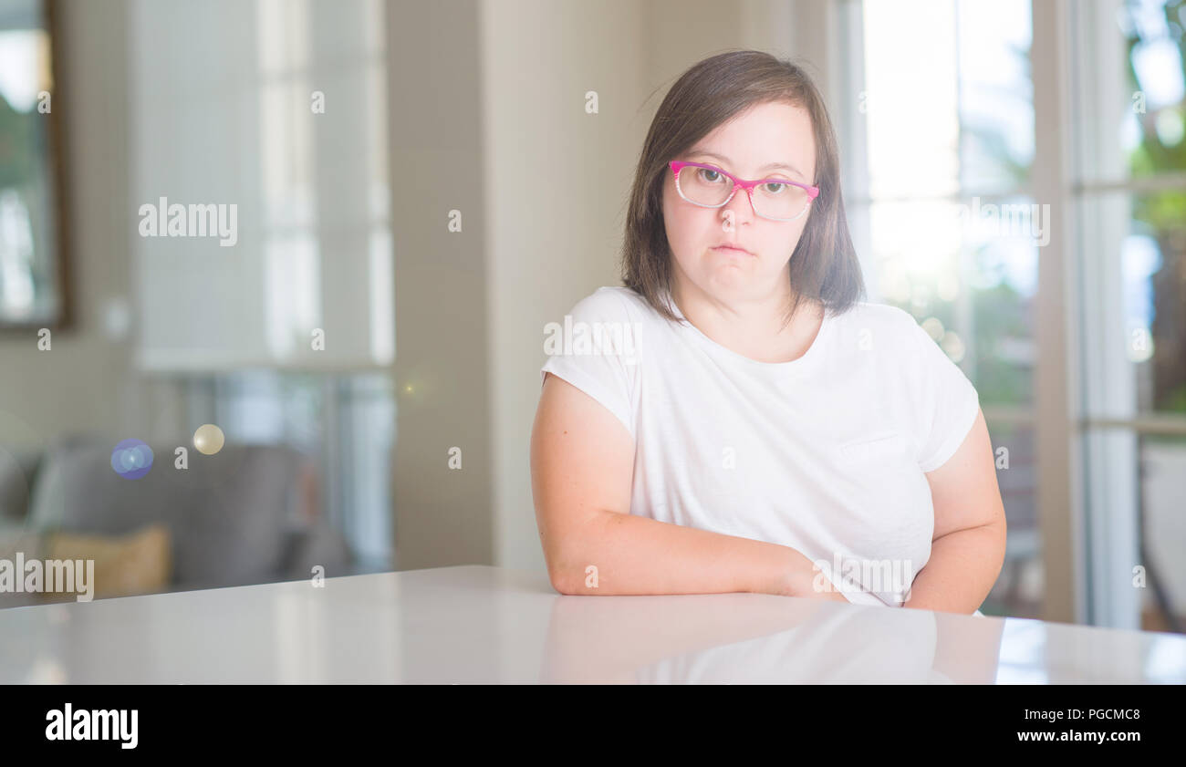 Down syndrome woman at home with a confident expression on smart face ...