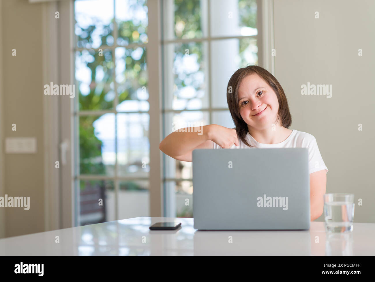 Down syndrome woman at home using computer laptop with surprise face ...