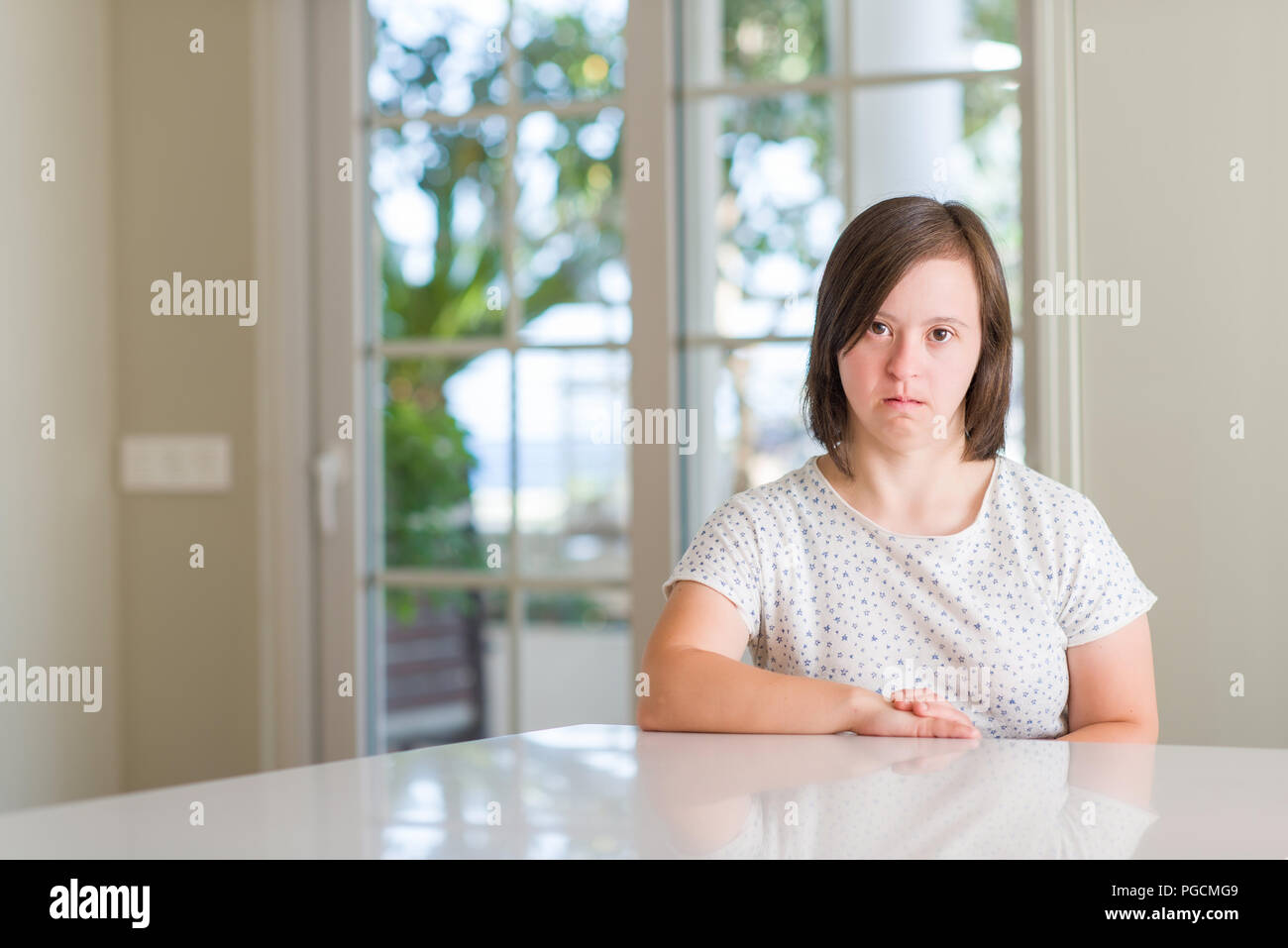 Down syndrome woman at home with a confident expression on smart face ...