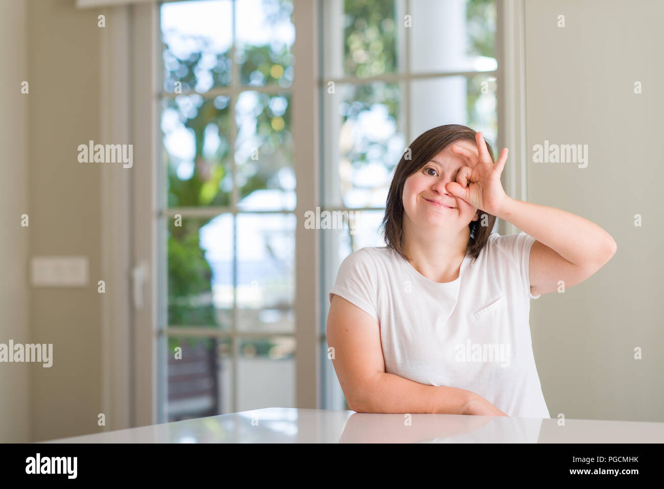 Down syndrome woman at home doing ok gesture with hand smiling, eye ...