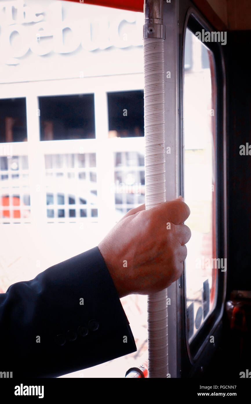 Old Fashioned type of Bus Conductor holding on to the rail of the rear ...