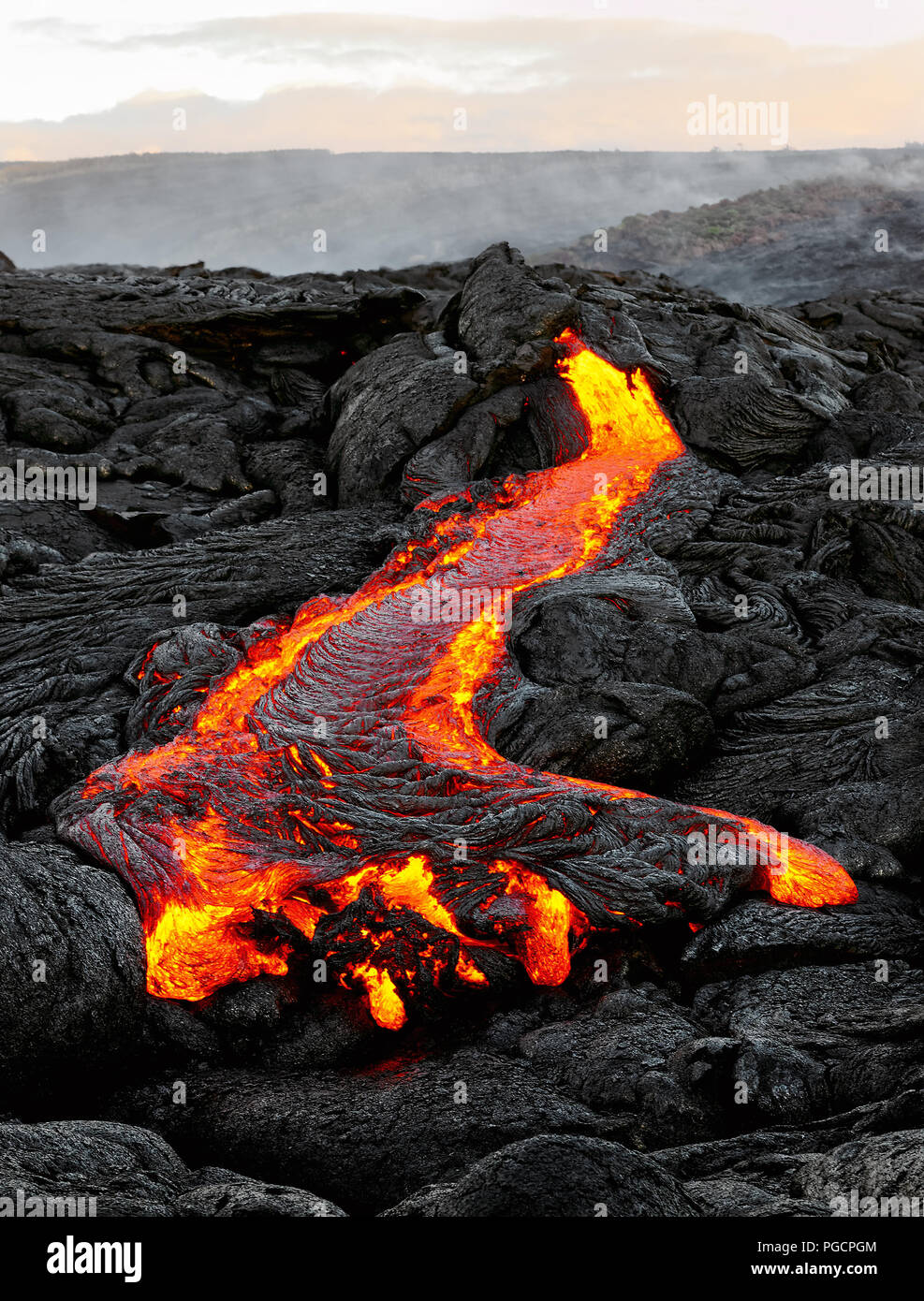 A lava flow emerges from an earth column and flows in a black volcanic ...