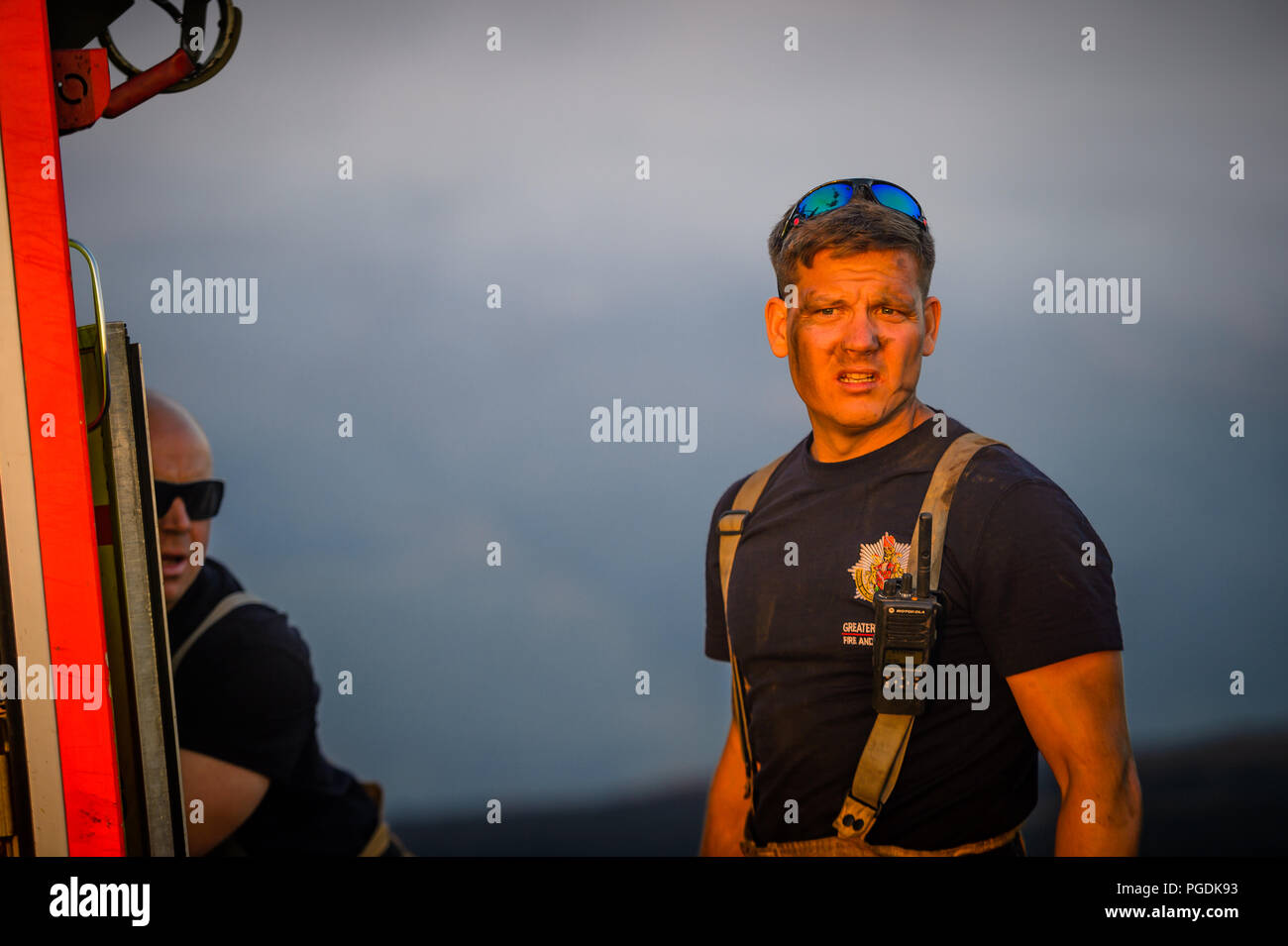 A fire fighter with a sooty face stands taking a break during the ...