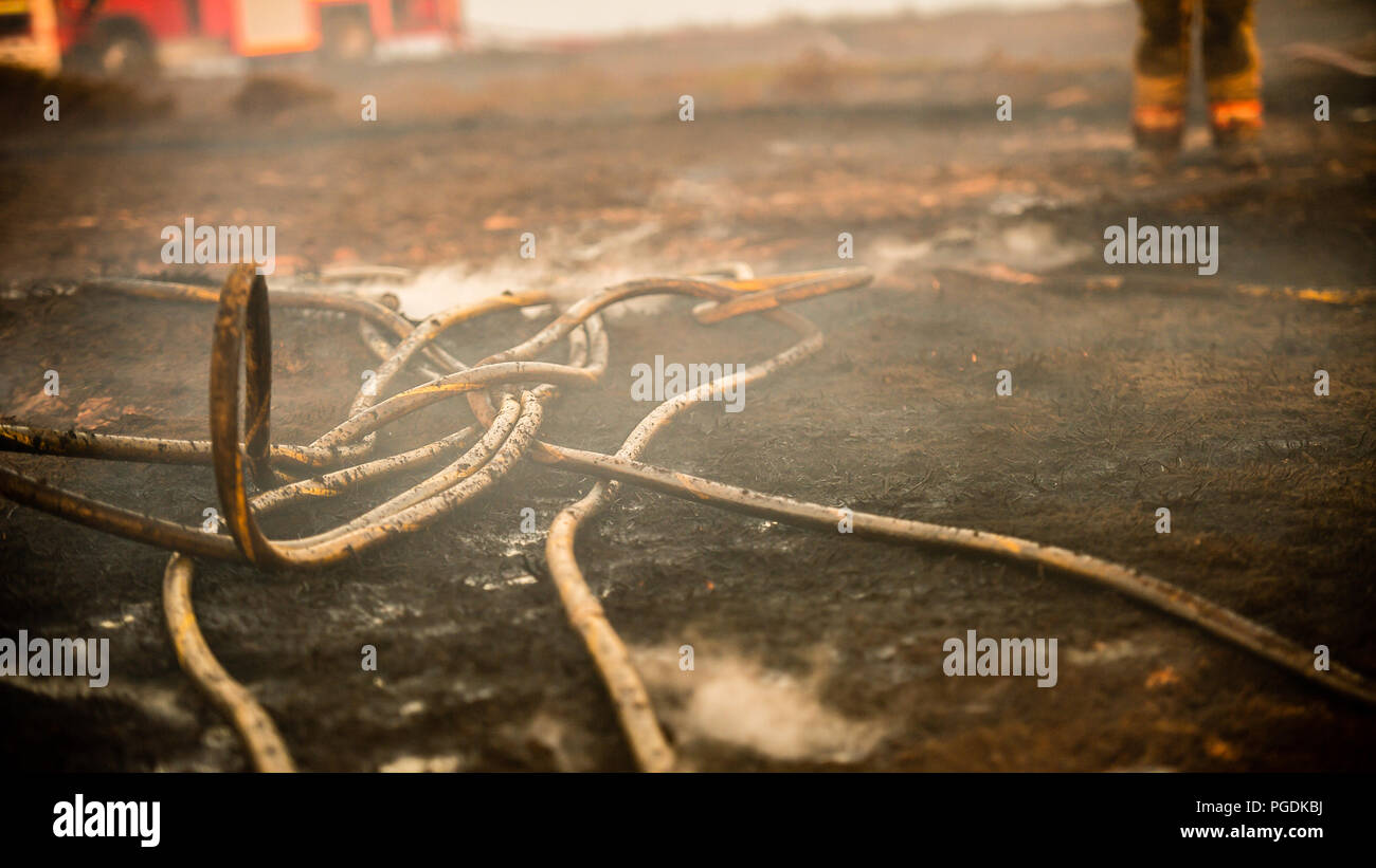 Fire hoses sit on the smouldering hot ground during the Saddleworth ...