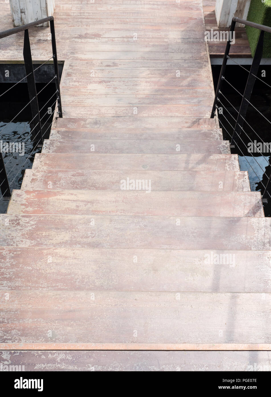 Modern wooden staircase is over the small pond to the wooden floor in ...