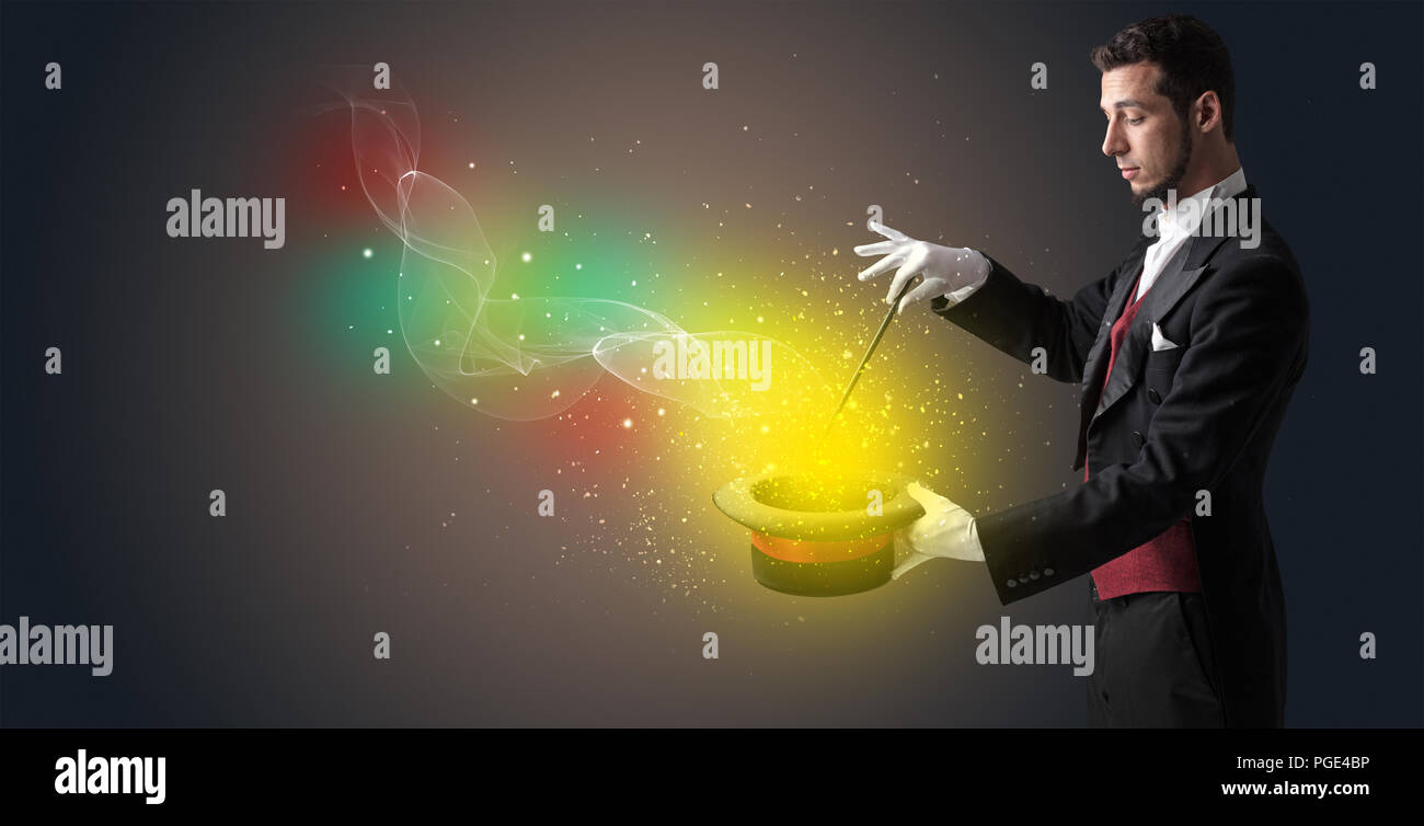 Illusionist hand starts to conjure with white glove and magic wand ...