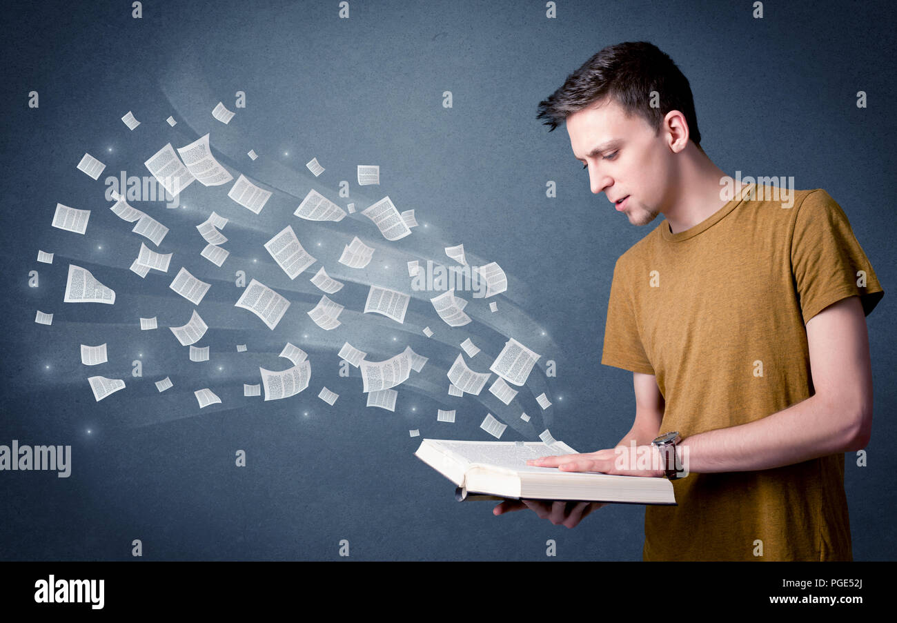 Casual young man holding book with pages flying out of it Stock Photo ...