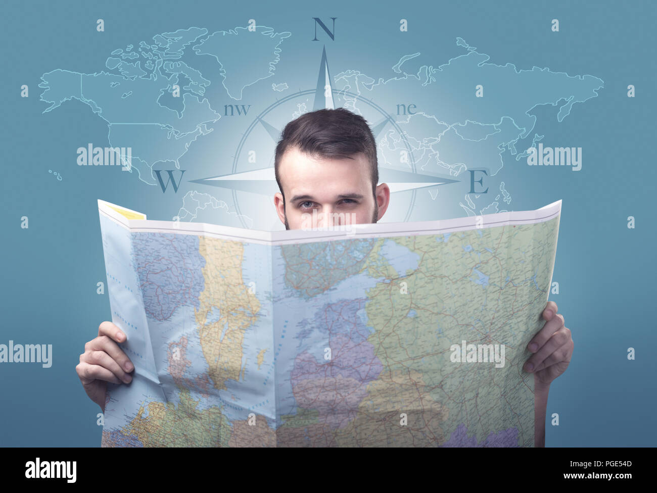 Handsome young man holding a map with a world map and a compass behind ...