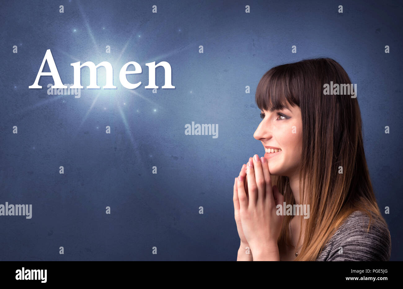 Young woman praying on a blue background with the word Amen written ...