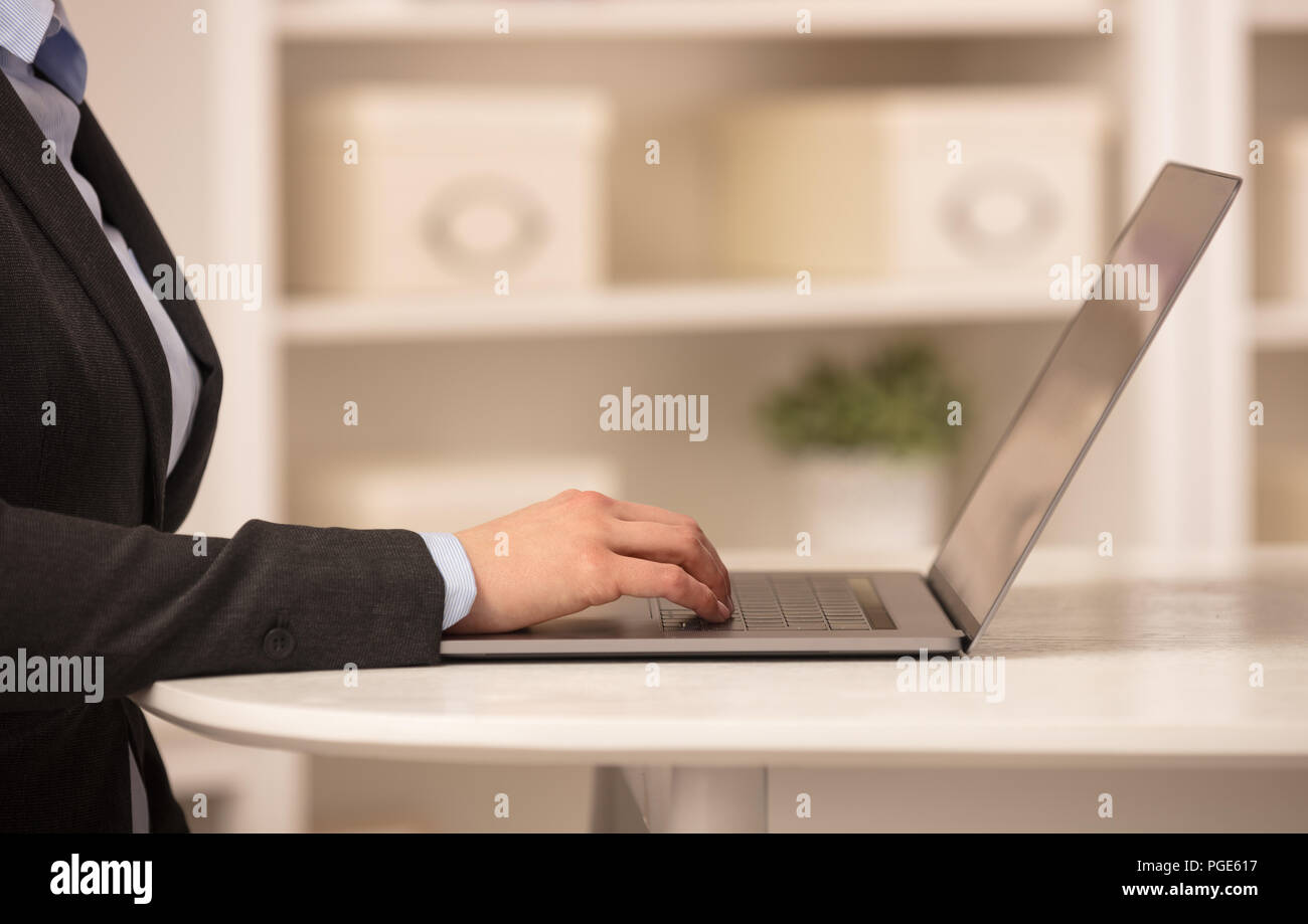 Business woman below chest working on her laptop in a cozy environment ...