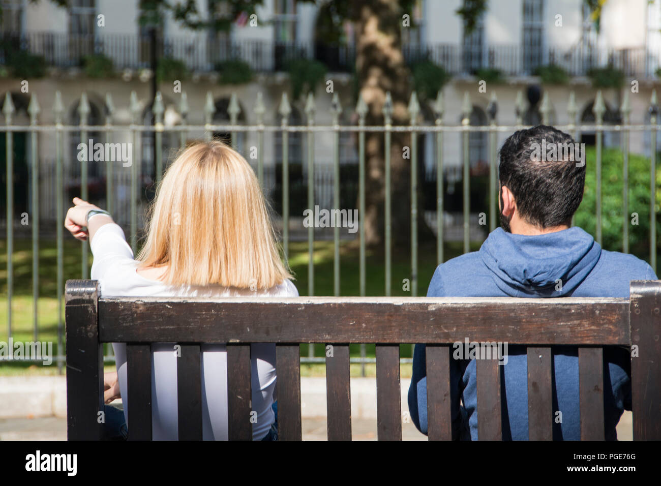 A woman pointing from a park bench on Fitzroy Square, London, W1, UK ...