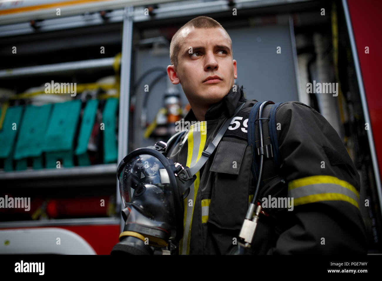 Photo of young fireman near fire engine Stock Photo - Alamy