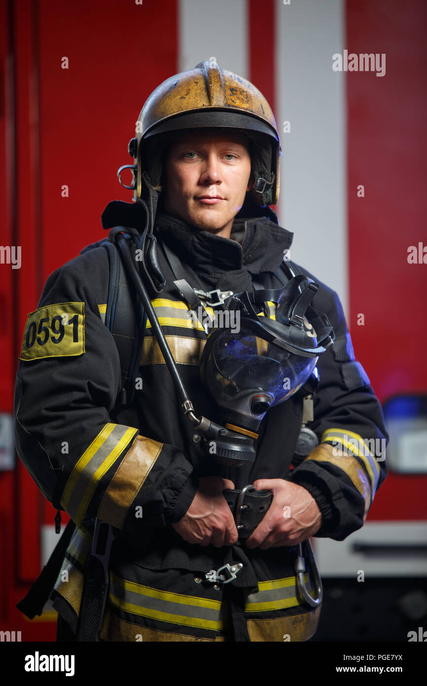 Photo of young fireman wearing helmet with gas mask on background of ...