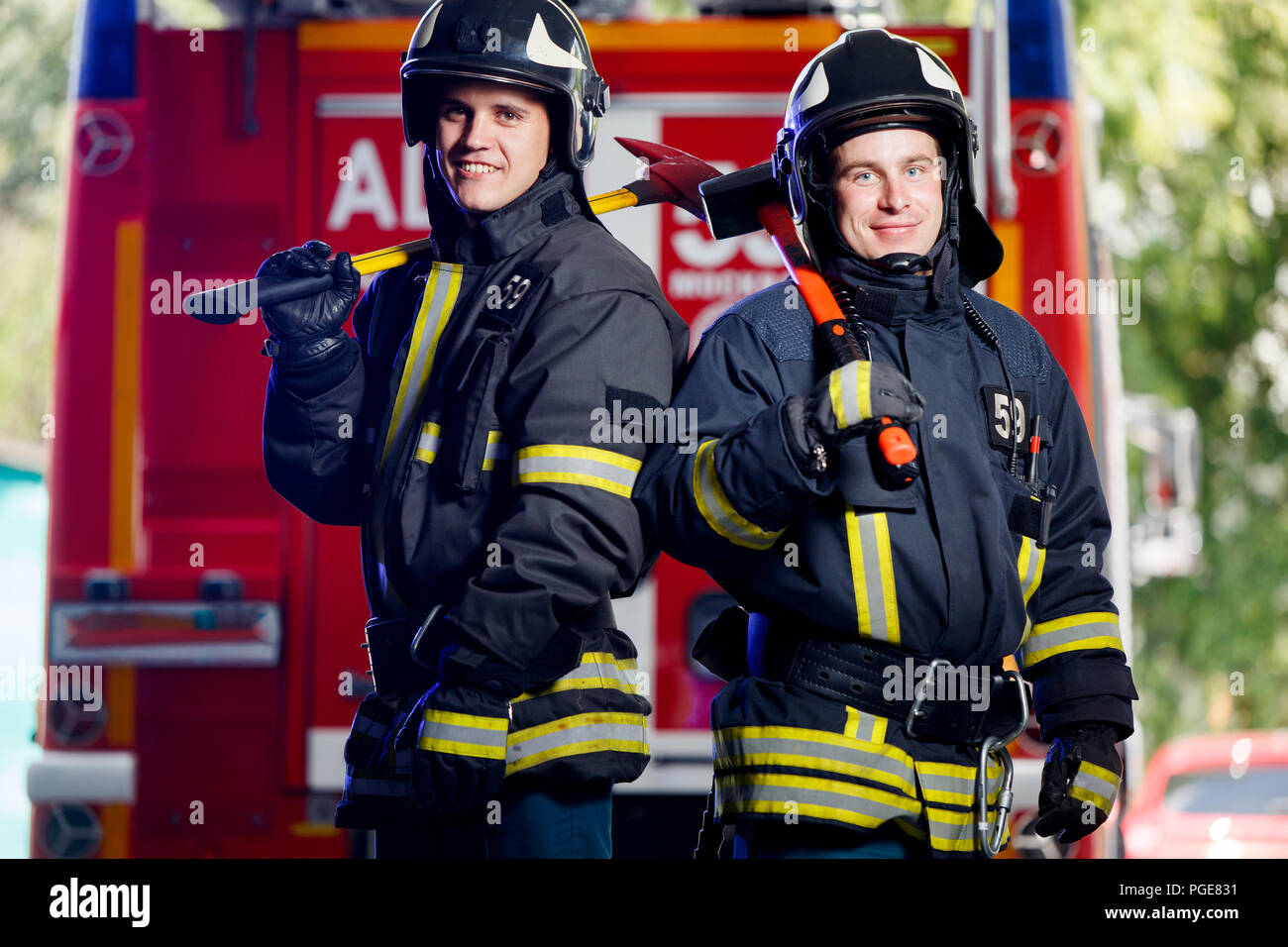Photo of two young firemen with axes in hands near fire engine Stock ...