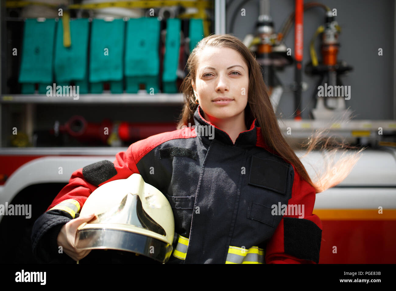Photo of young firefighter woman staring into camera with long hair ...