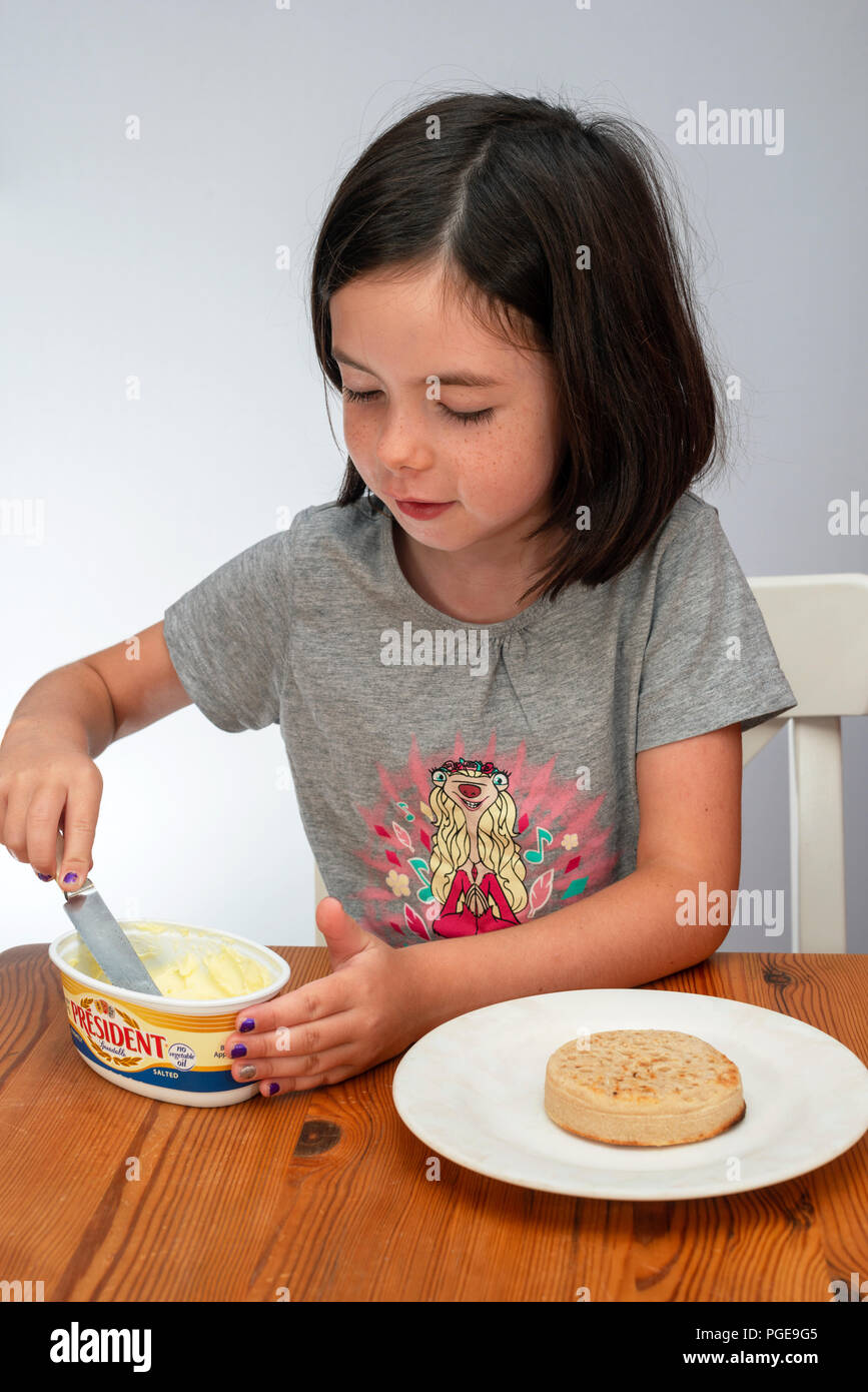 Young girl buttering a crumpet Stock Photo - Alamy